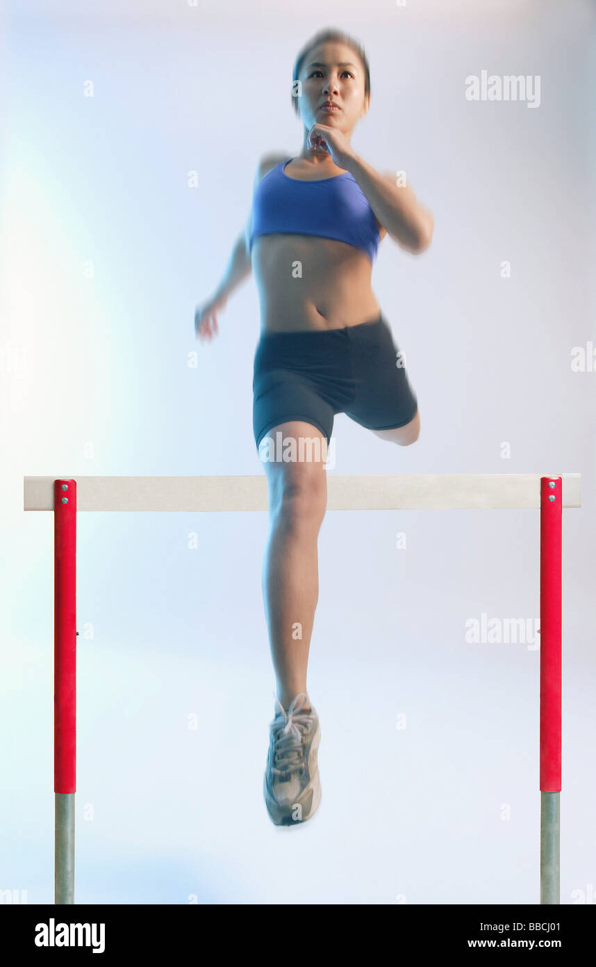 Woman running and jumping over hurdle Stock Photo - Alamy