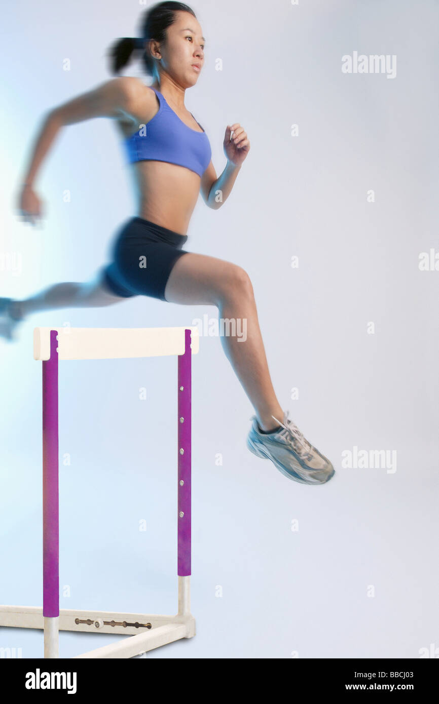 Woman jumping over hurdle Stock Photo - Alamy