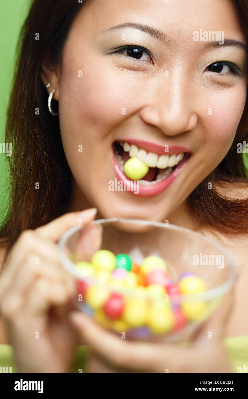Woman biting candy and holding candy bowl Stock Photo - Alamy