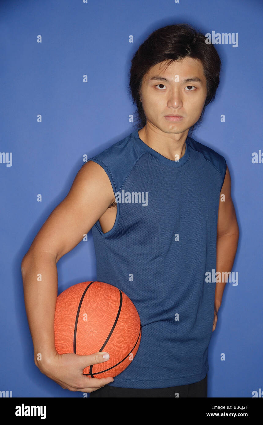 Man holding basketball under arm, looking at camera Stock Photo - Alamy