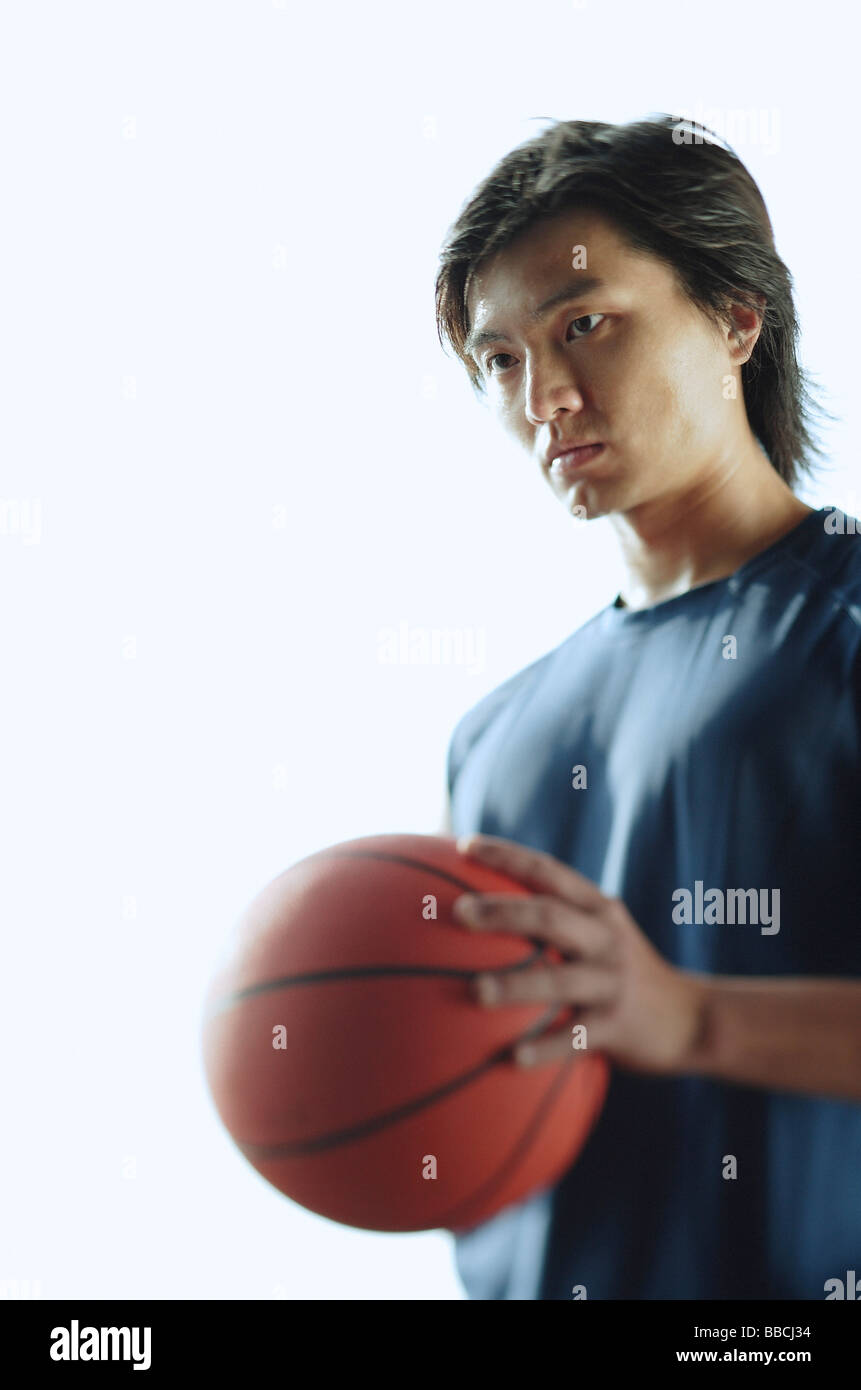 Man holding basketball, looking away Stock Photo - Alamy