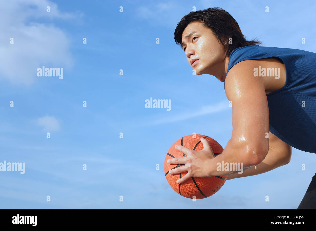 Man holding basketball, looking away, side view Stock Photo - Alamy