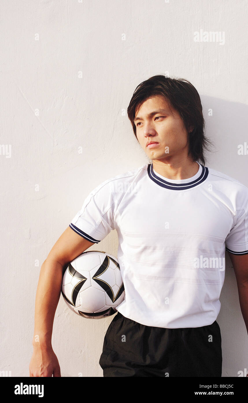 Man holding soccer ball under arm Stock Photo - Alamy