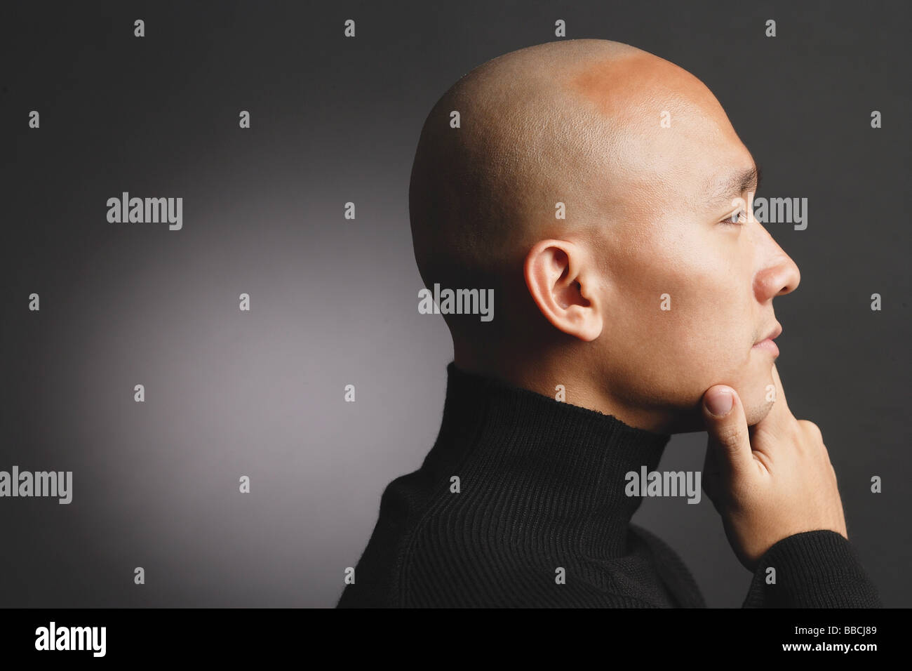 Man with shaved head, hand on chin, profile Stock Photo - Alamy
