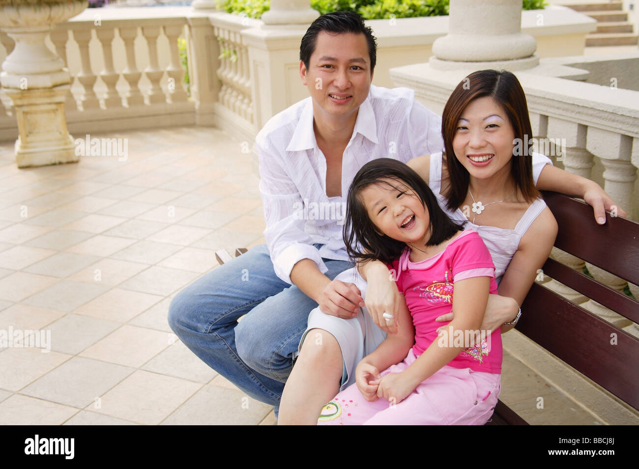 Family with one child, sitting on bench, looking up at camera Stock ...