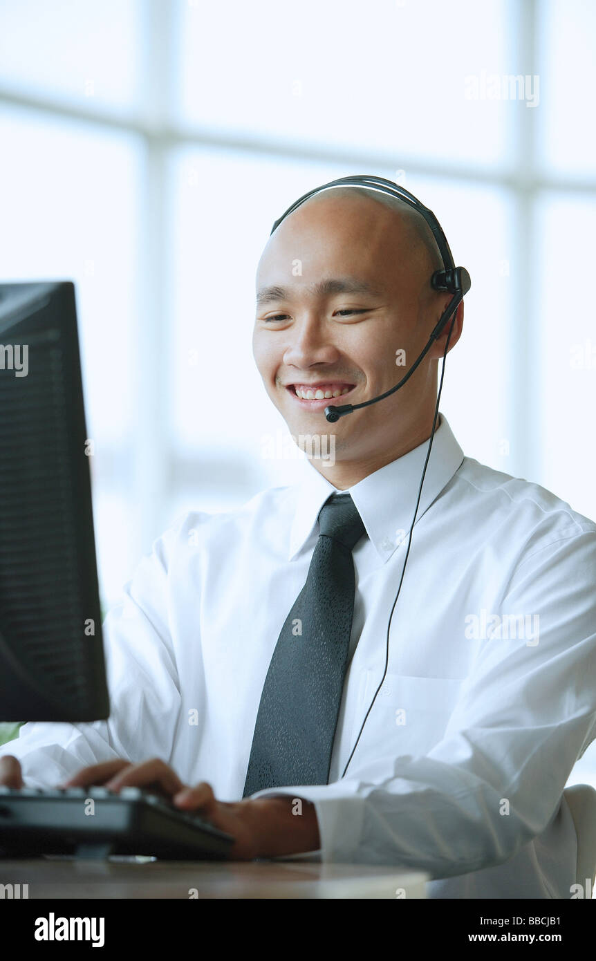 Man with headset, smiling, using computer Stock Photo - Alamy