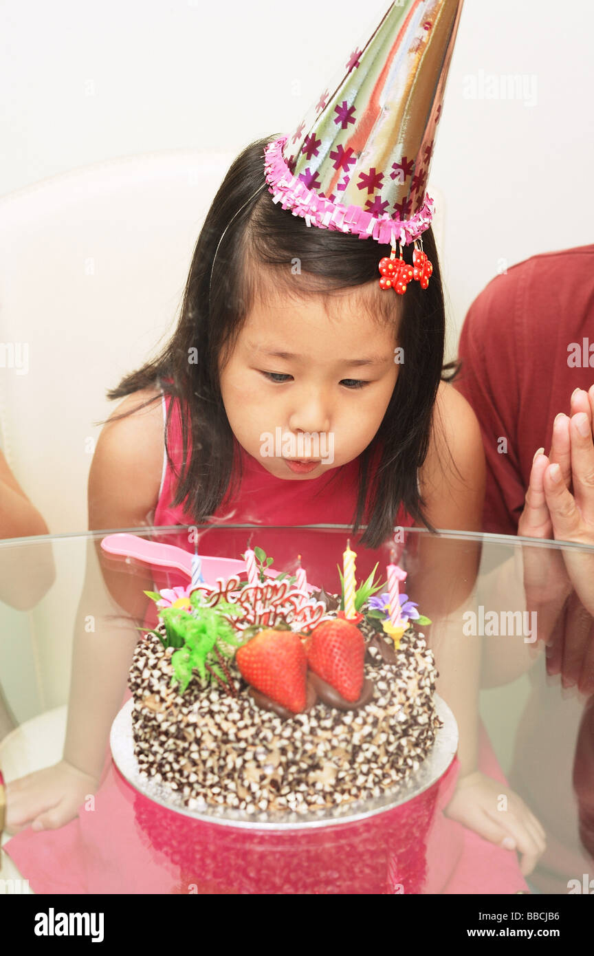 Girl blowing out birthday cake Stock Photo - Alamy