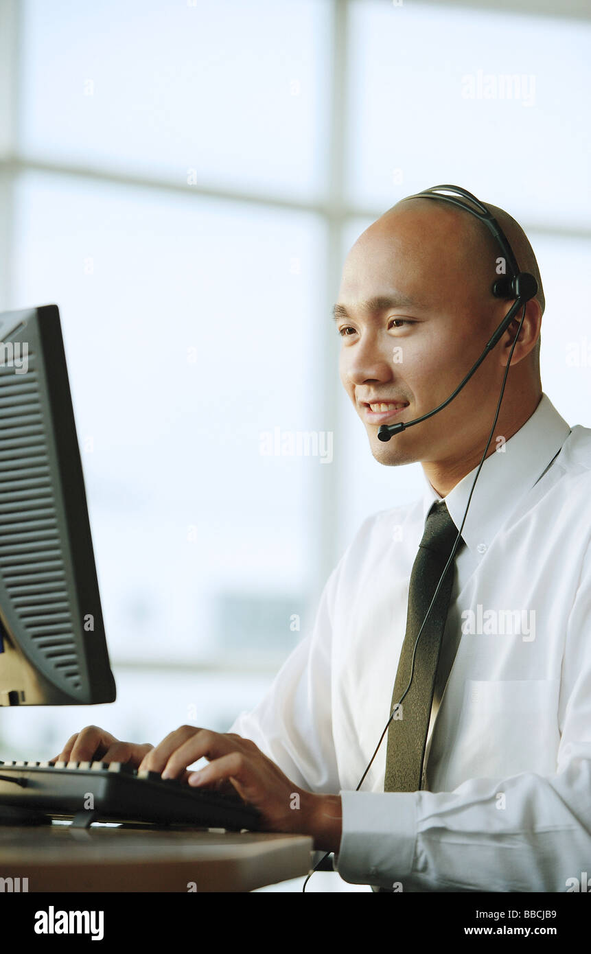 Man with headset, in front of computer, smiling Stock Photo - Alamy