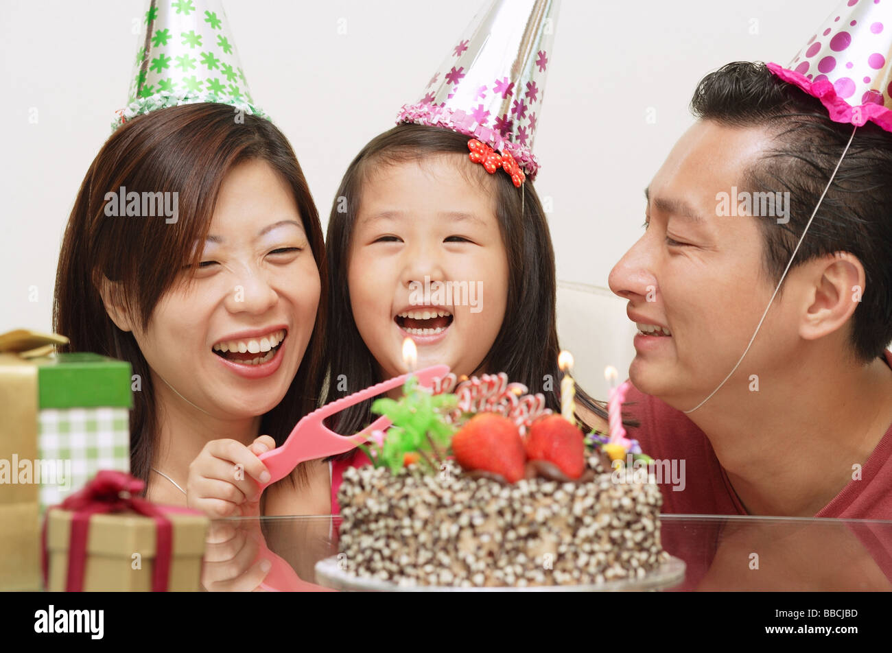 Girl with birthday cake, parents on either side smiling Stock Photo - Alamy
