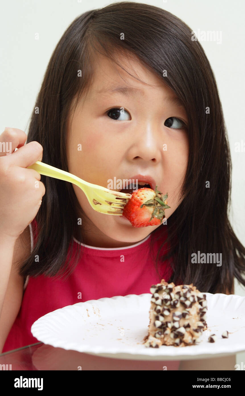 Young girl eating strawberry with fork Stock Photo - Alamy