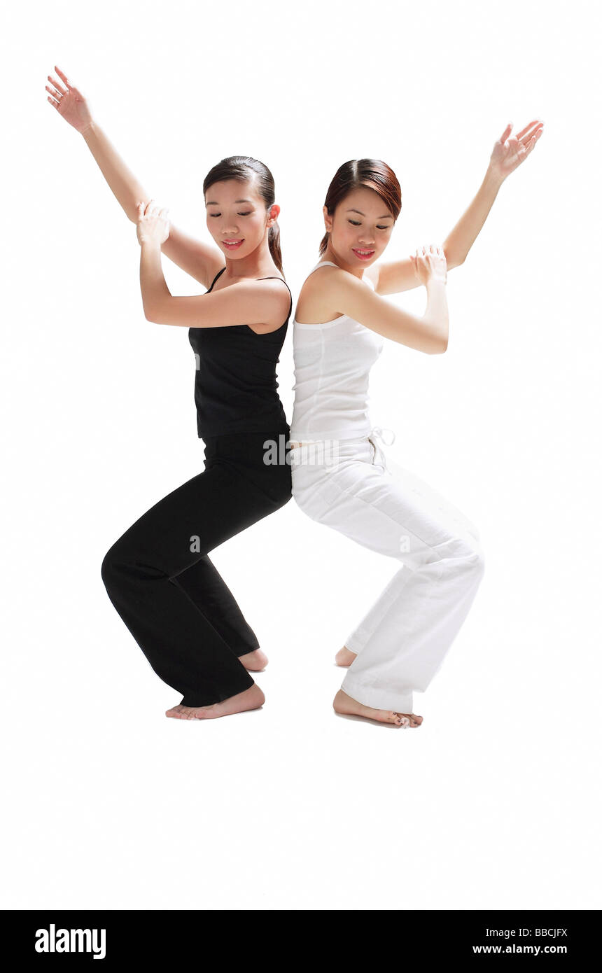 Two women back to back, bending knees, arms outstretched Stock Photo ...