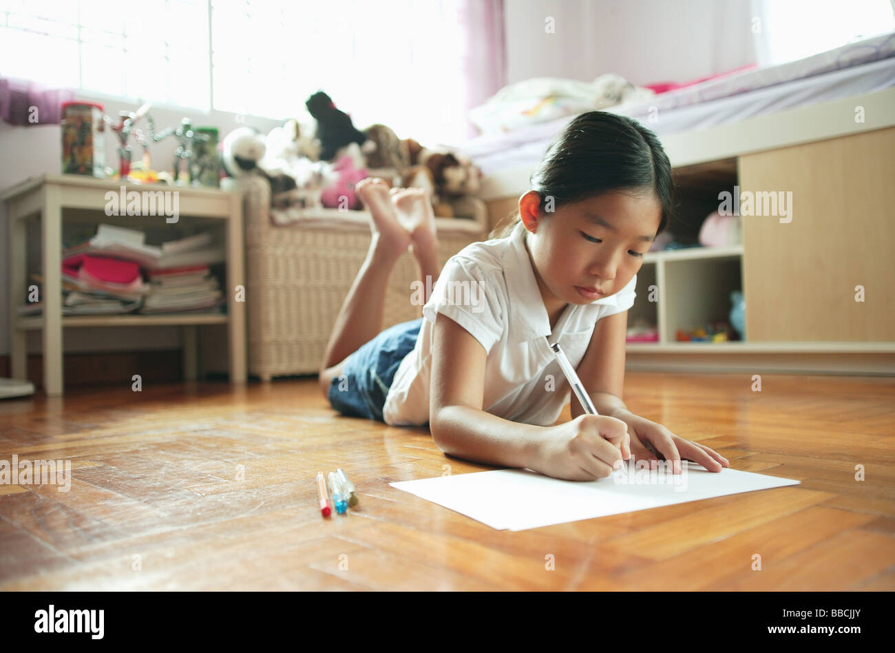 Girl in bedroom, lying on floor, drawing on paper Stock Photo - Alamy