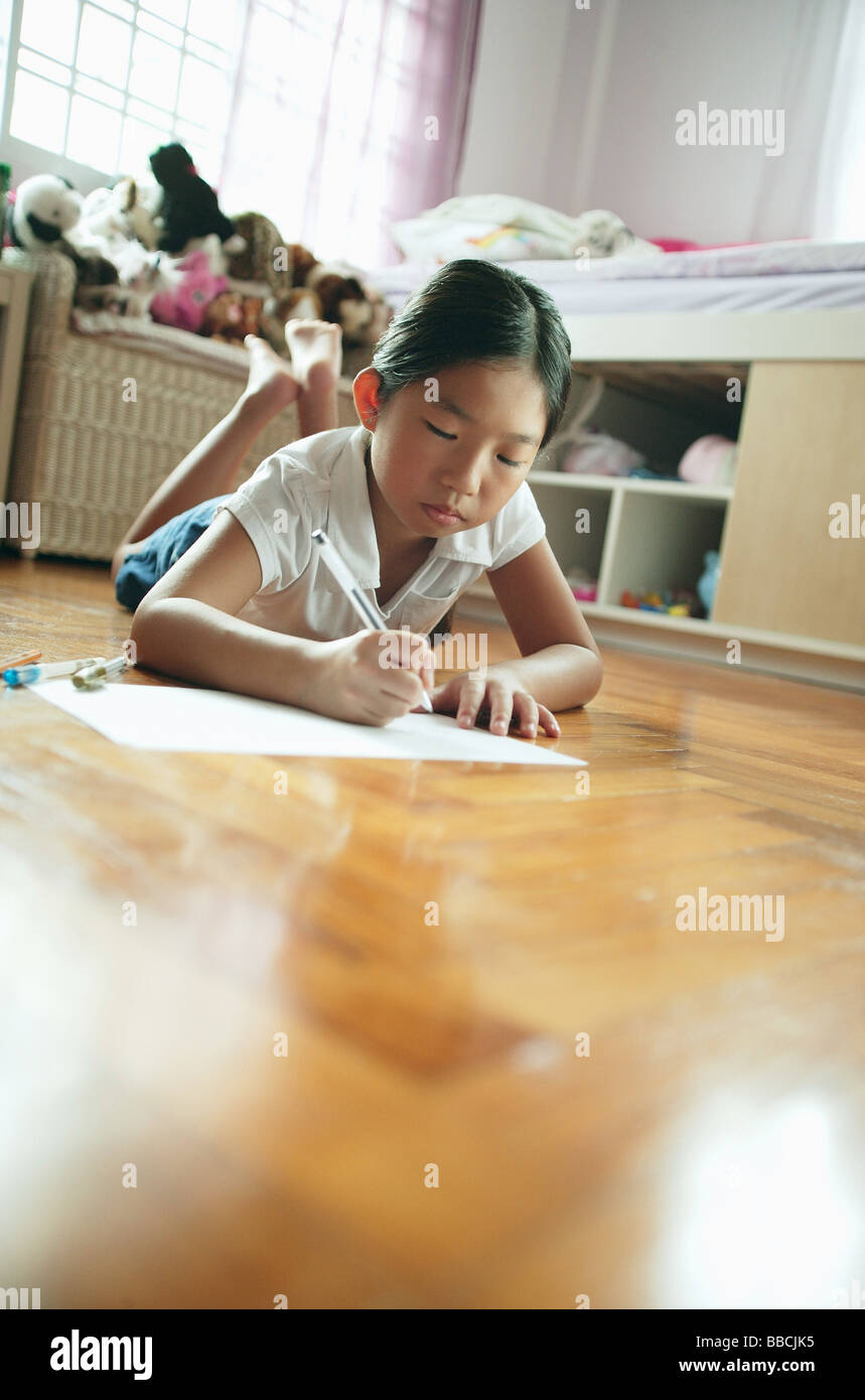 Girl in bedroom, lying on floor, writing on paper Stock Photo - Alamy