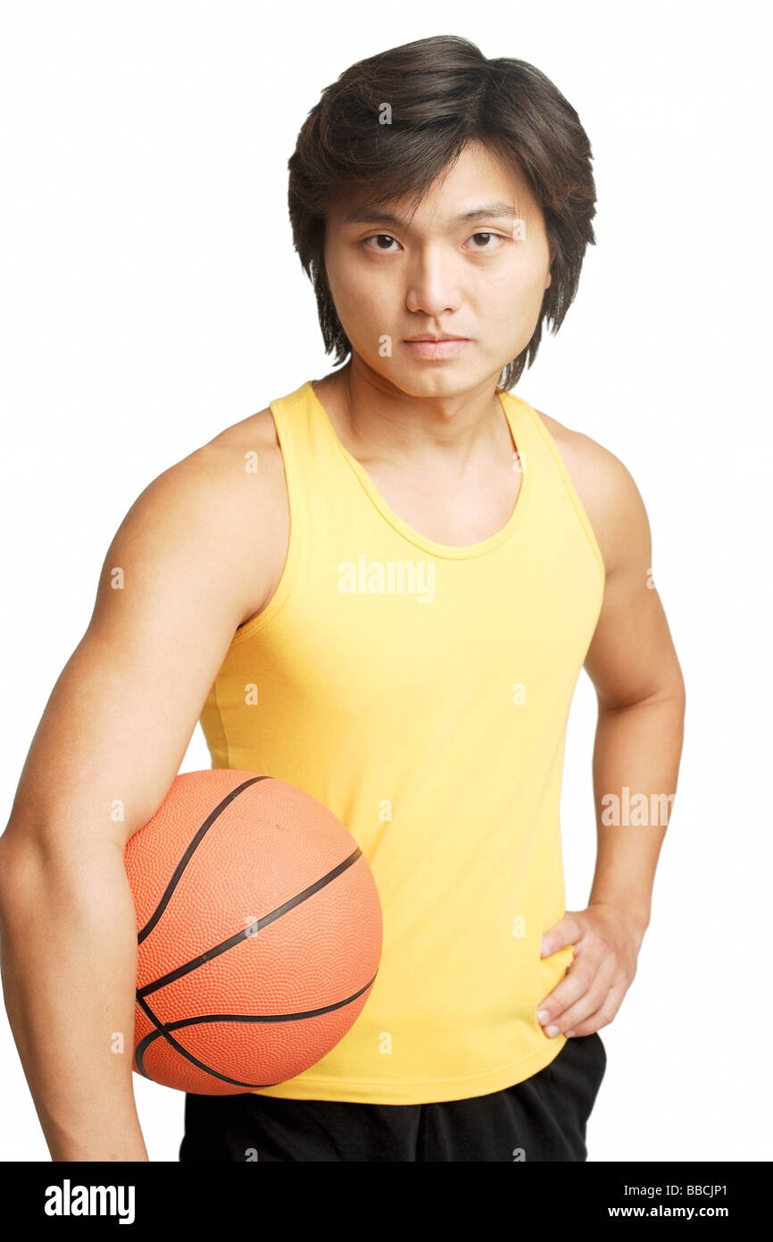 Man with basketball under arm, hand on hip, looking at camera, portrait ...
