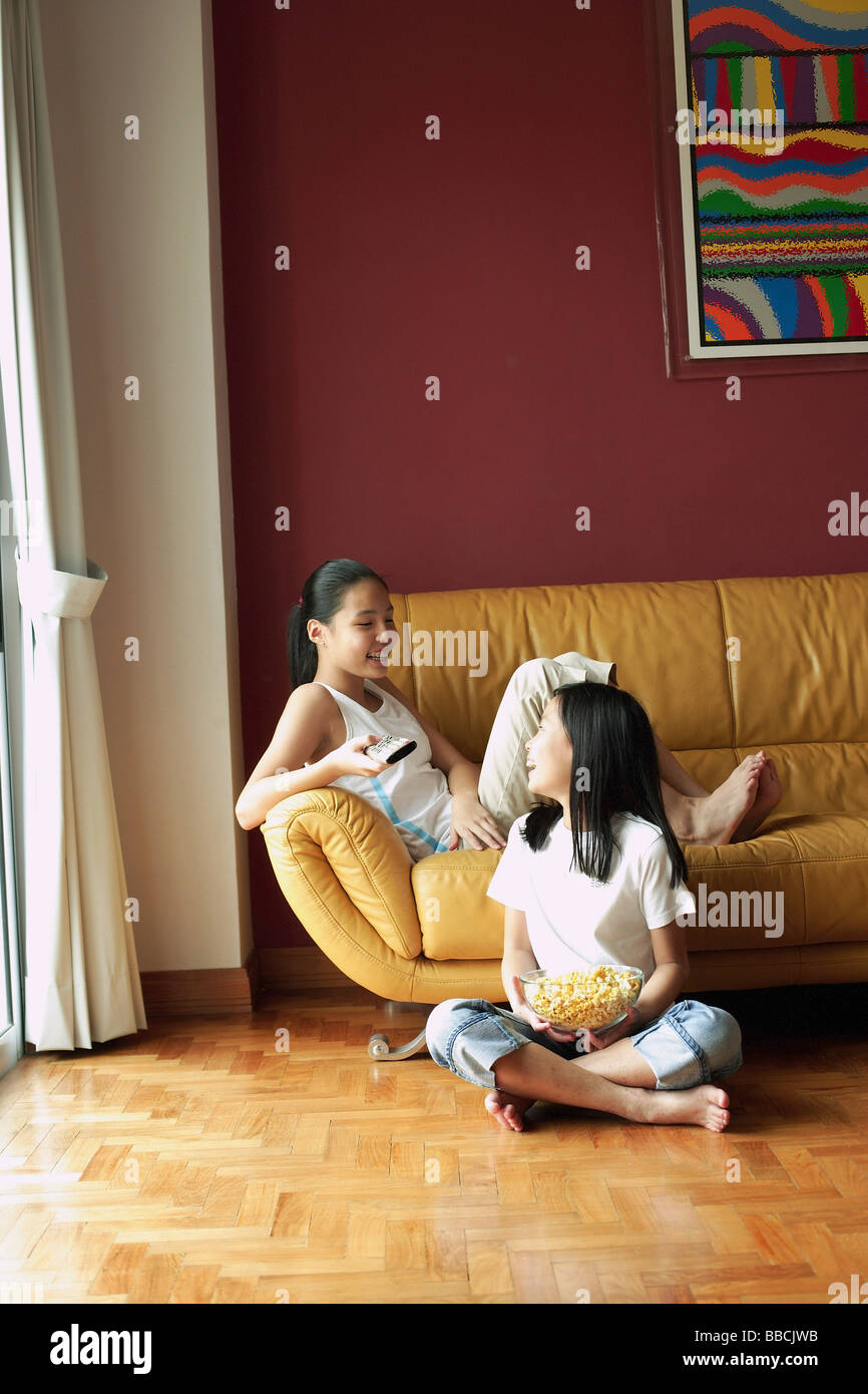 Two girls sitting in living room, talking Stock Photo - Alamy