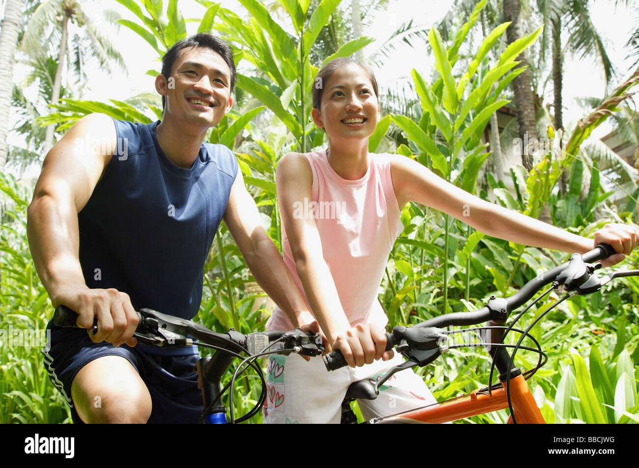 Man and Woman riding bikes through a park, smiling Stock Photo - Alamy
