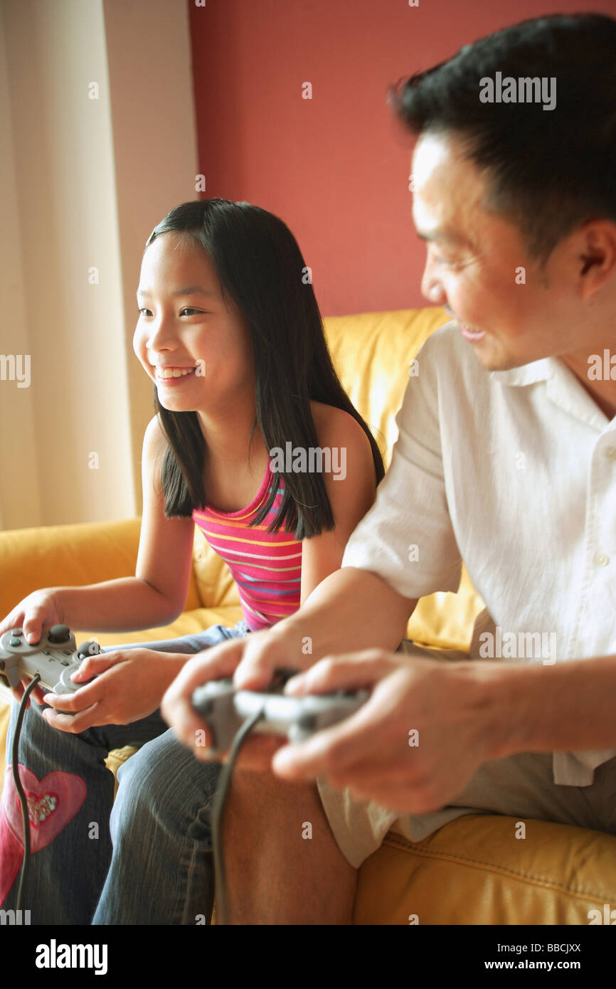 Father and daughter playing video games, father looking at daughter ...