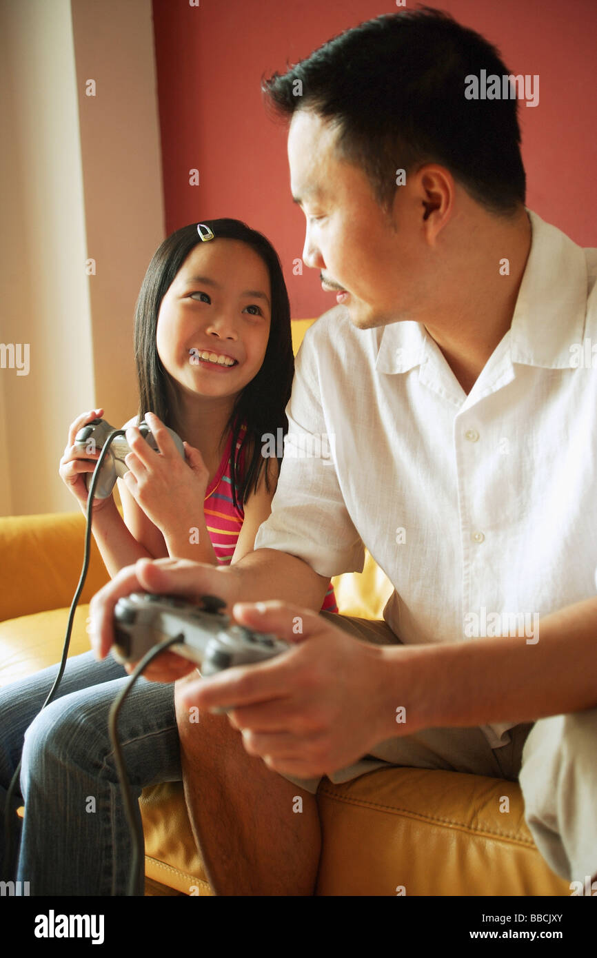 Father and daughter looking at each other, holding video game ...