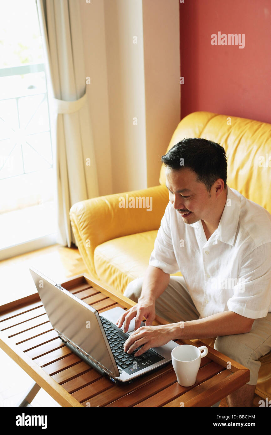 Man sitting in living room, using laptop Stock Photo - Alamy