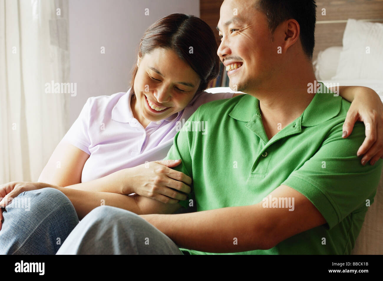 Couple sitting side by side, laughing Stock Photo - Alamy