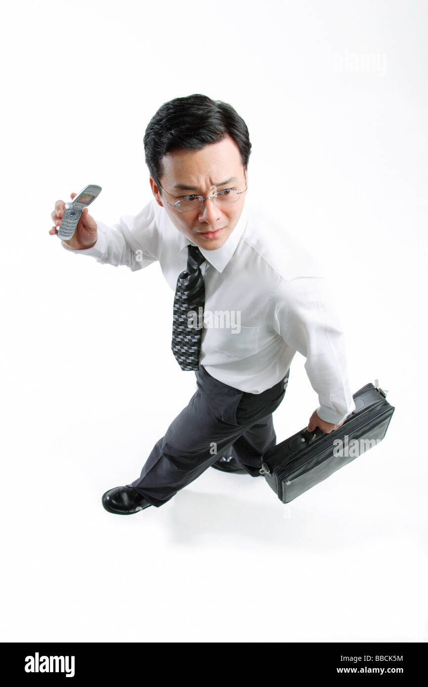 Businessman carrying briefcase and mobile phone, walking Stock Photo ...