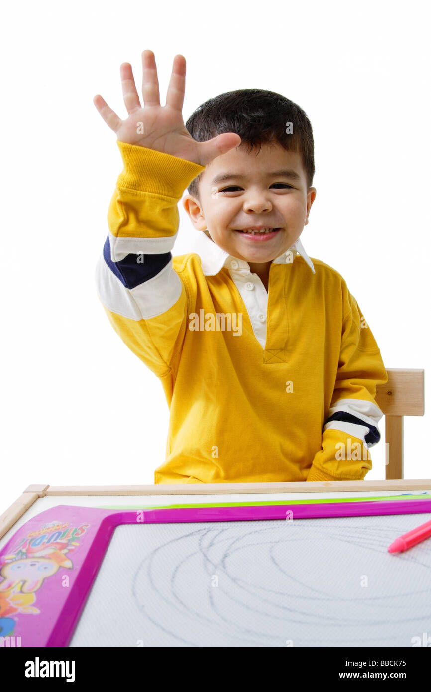 Boy sitting, smiling at camera, raising hand Stock Photo - Alamy