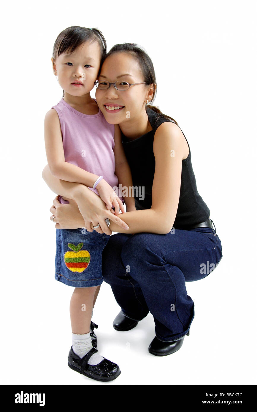 Young girl standing, mother crouching next to her, looking at camera ...