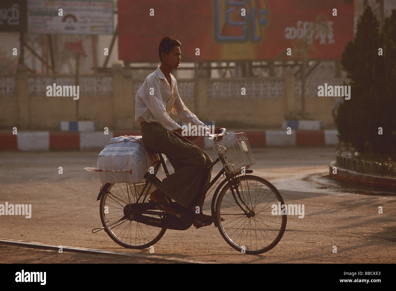 Myanmar (Burma), Pyay, Young man in longyi riding bicycle Stock Photo ...
