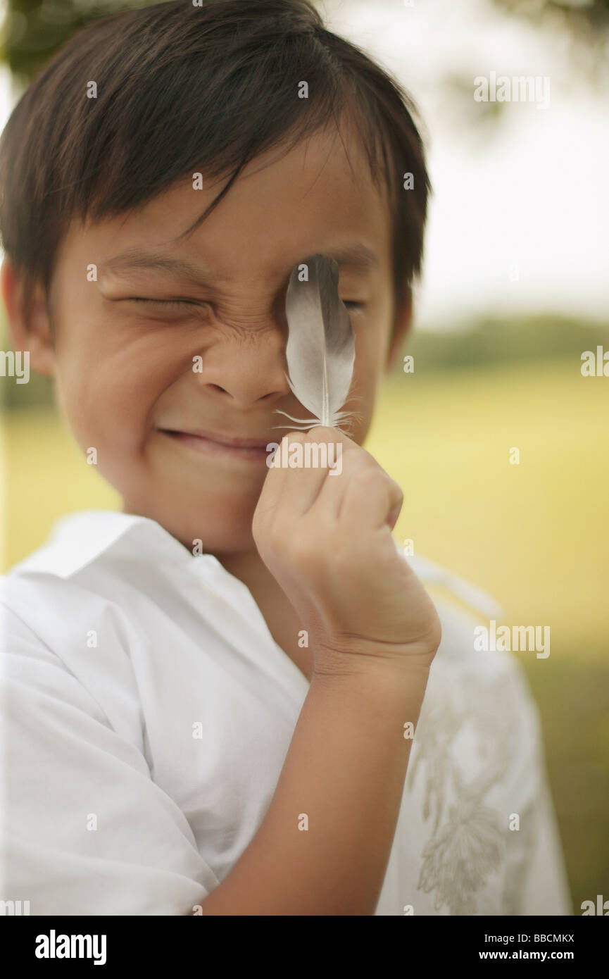 Young boy holding up feather to his face Stock Photo - Alamy