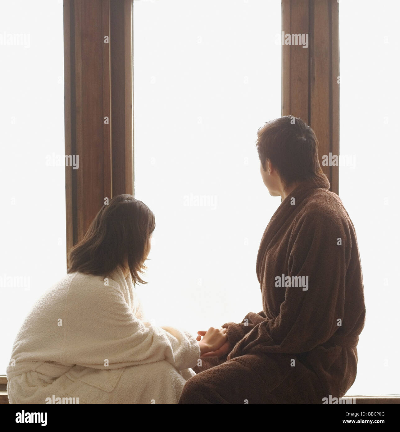 Couple in robes, looking at window Stock Photo - Alamy