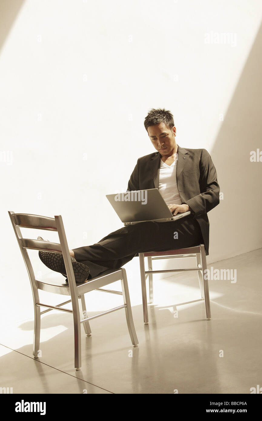 Man sitting down, using laptop Stock Photo - Alamy