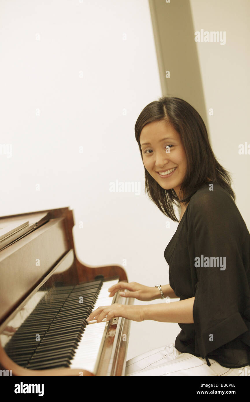 Woman at piano, looking at camera Stock Photo - Alamy