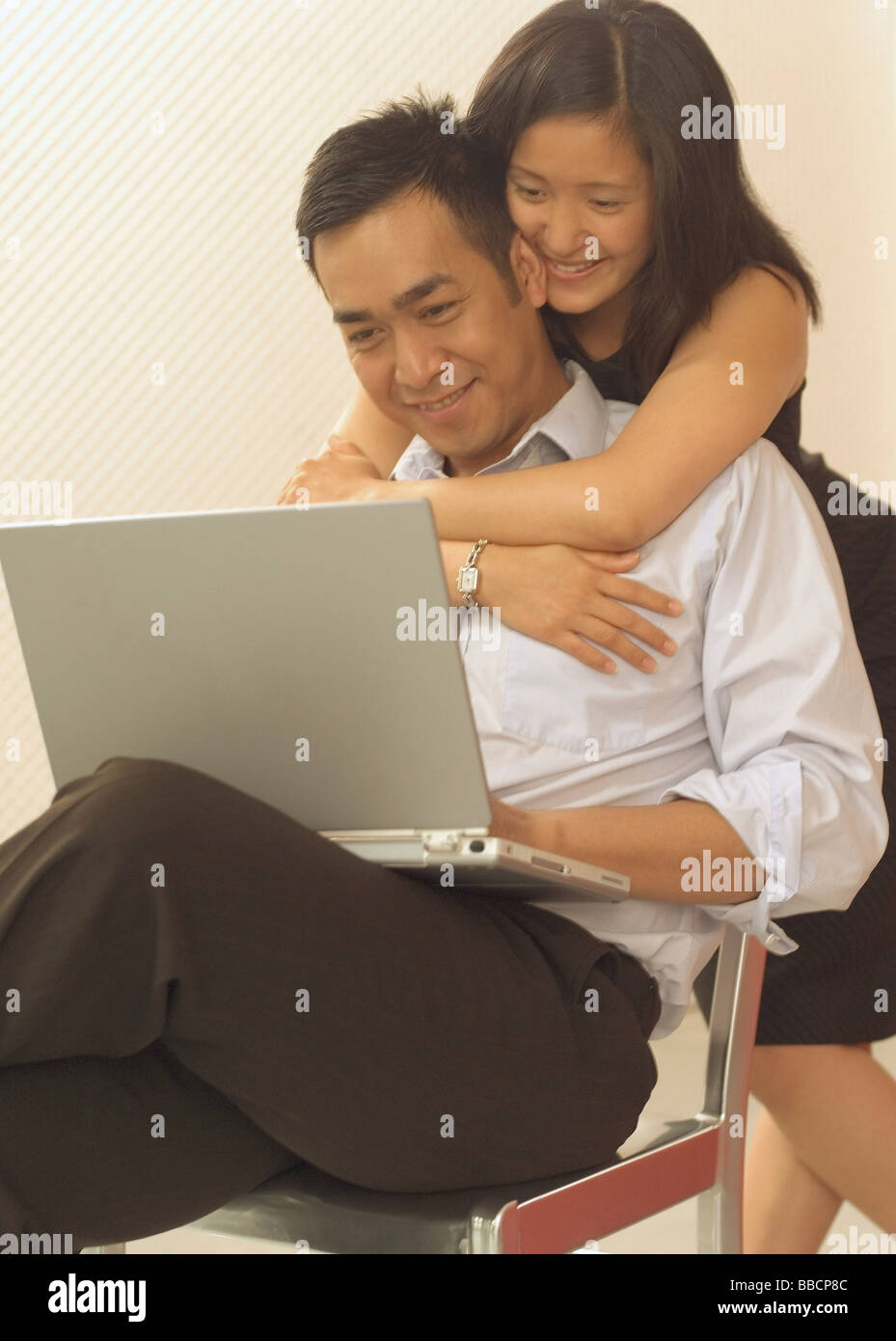 Man using laptop, woman hugging him Stock Photo - Alamy