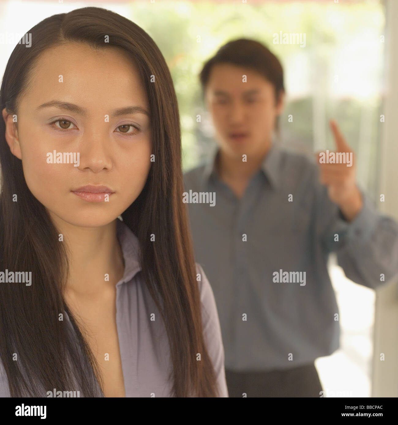 Woman looking at camera, man behind her gesturing Stock Photo - Alamy