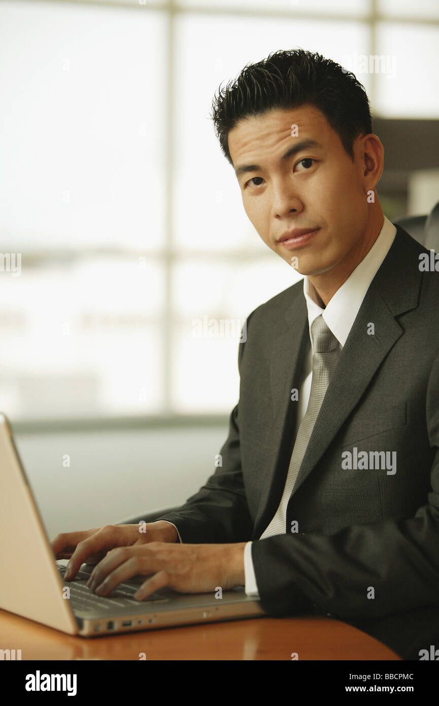 Young man looking at camera, using laptop Stock Photo - Alamy