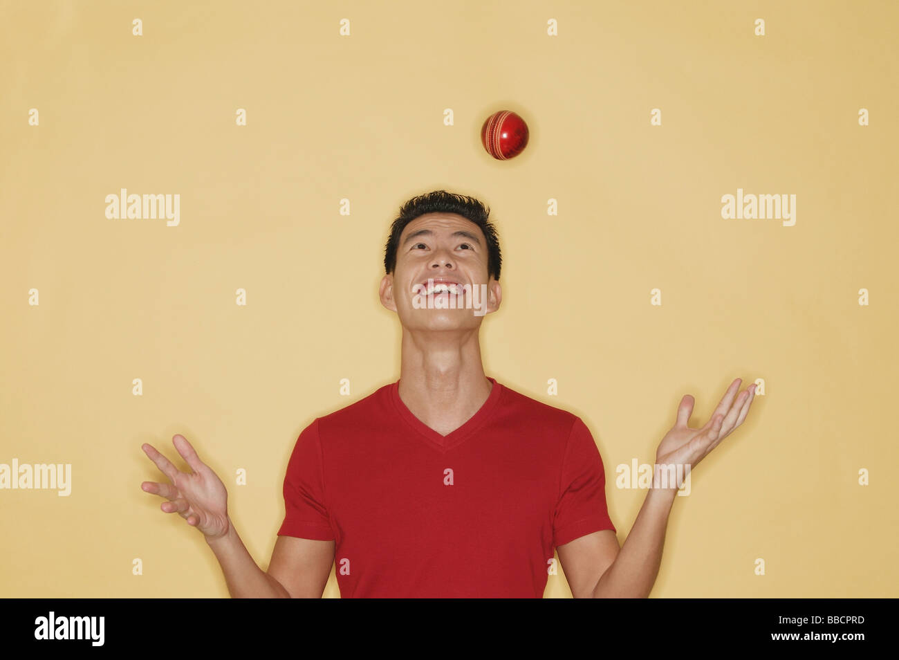 Young man juggling a ball, yellow background Stock Photo - Alamy