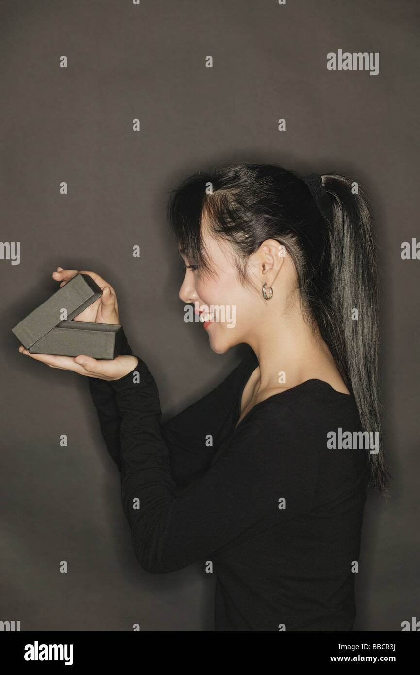 Young woman, side view, opening a box, black background Stock Photo - Alamy