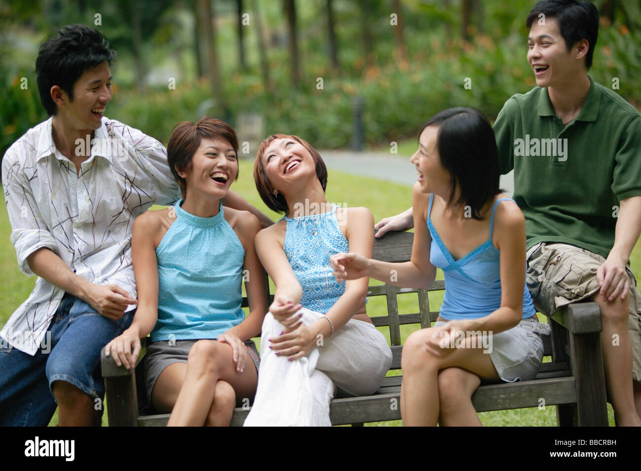 Friends sitting side by side on park bench, laughing Stock Photo - Alamy