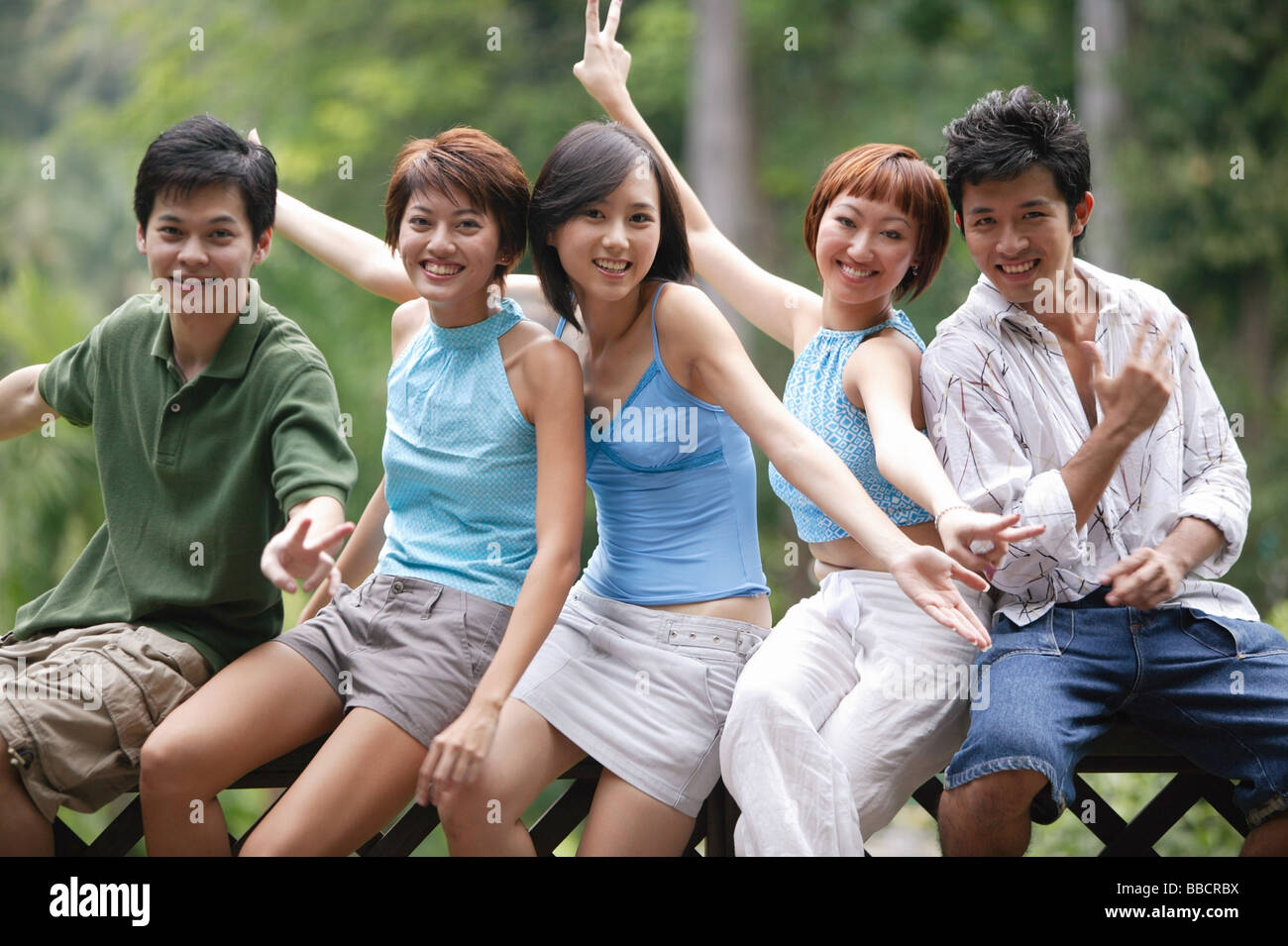 Friends sitting side by side, posing Stock Photo - Alamy