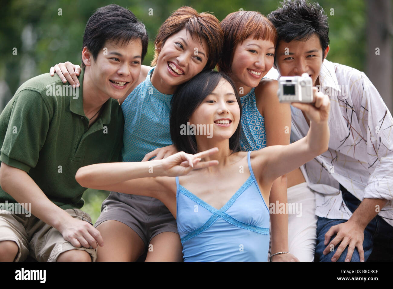 Friends sitting side by side, posing for camera Stock Photo - Alamy
