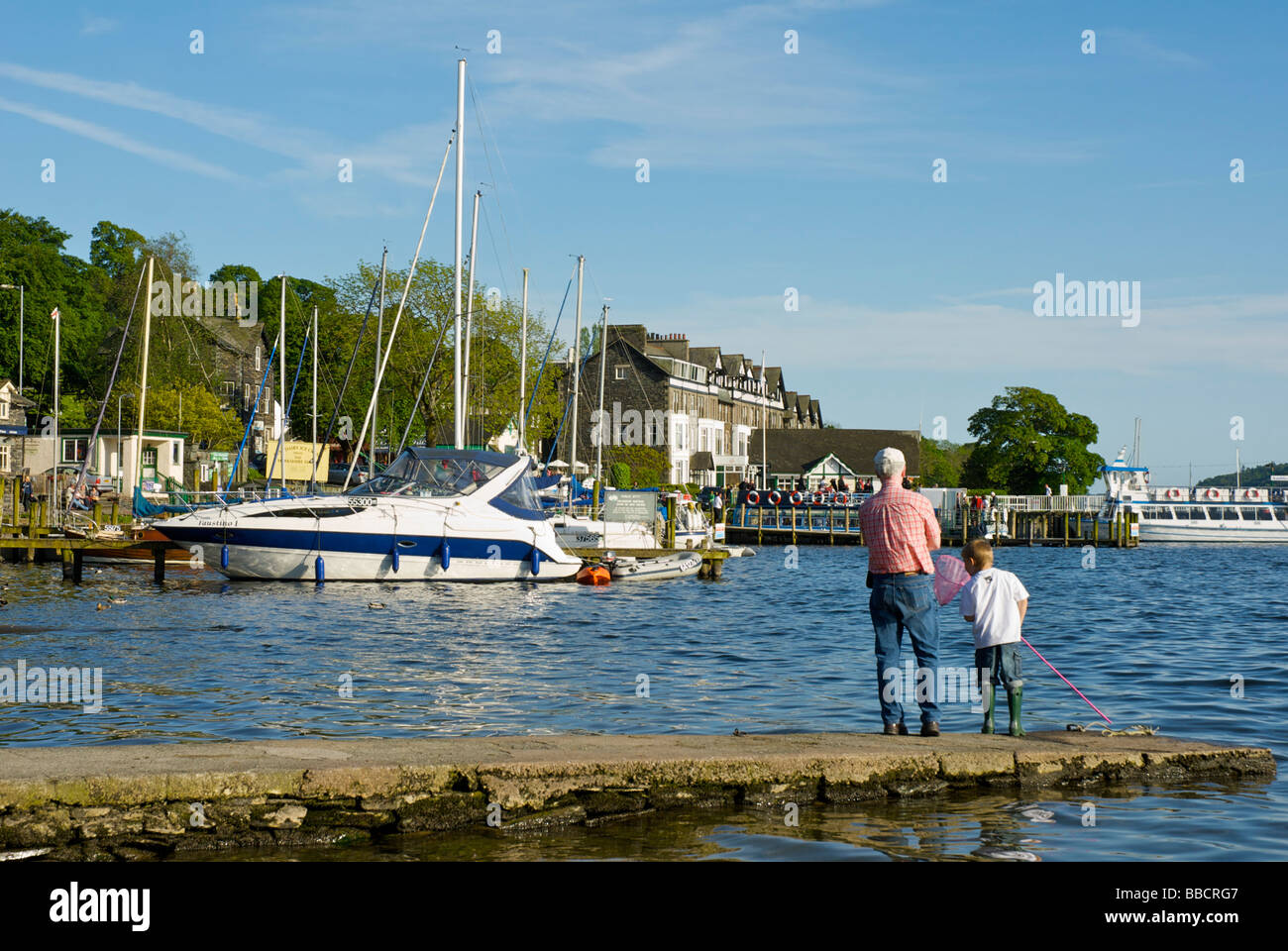 Man and boy on pier, Lake Windermere at Waterhead, Lake District ...