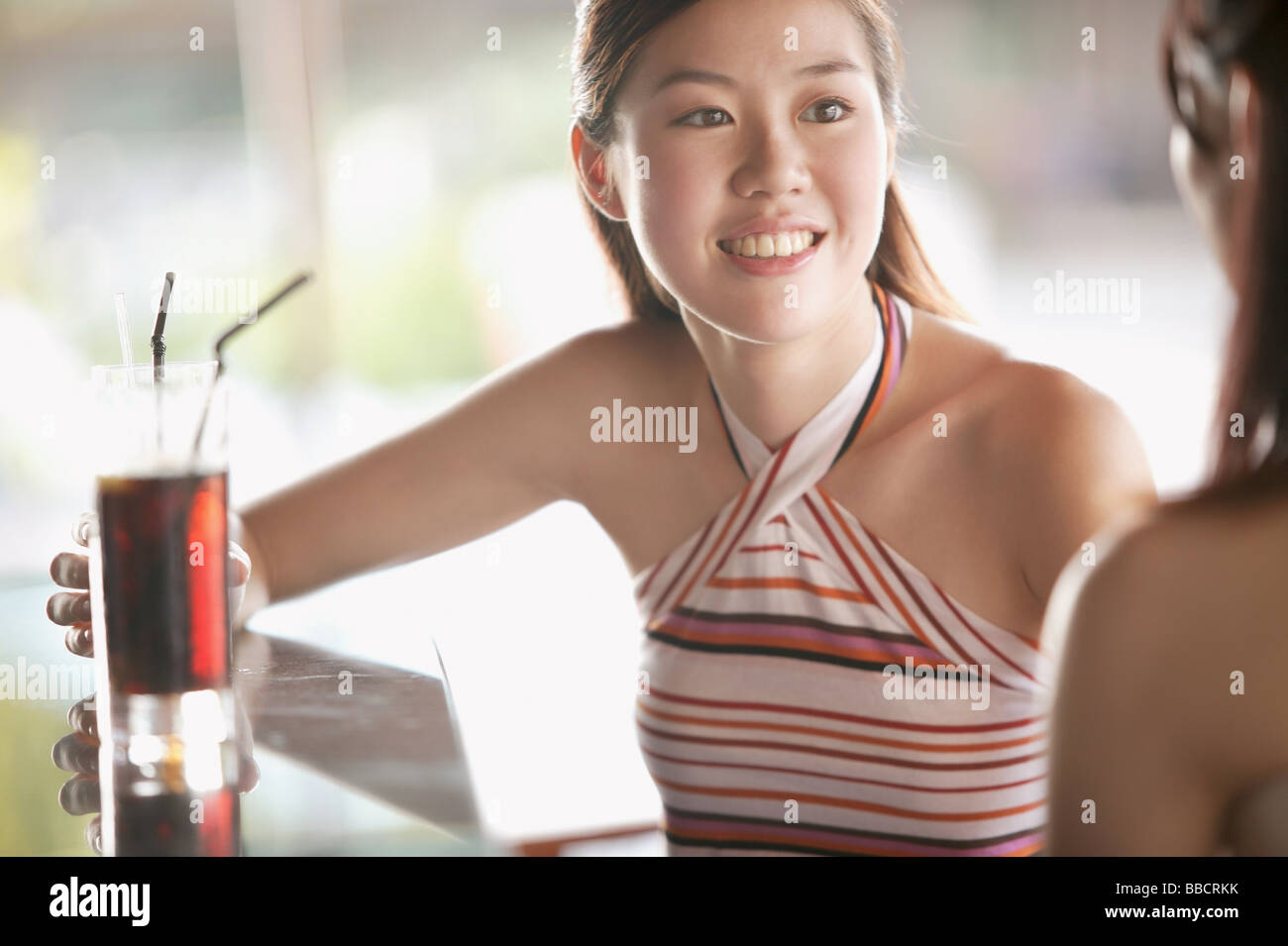 Two young women talking, face to face, drink on the table Stock Photo ...