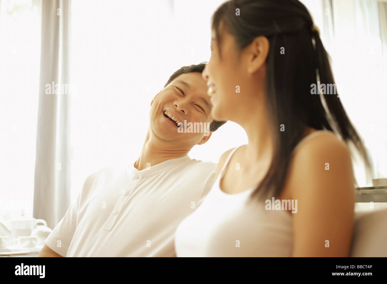 Couple sitting down side by side, laughing Stock Photo - Alamy