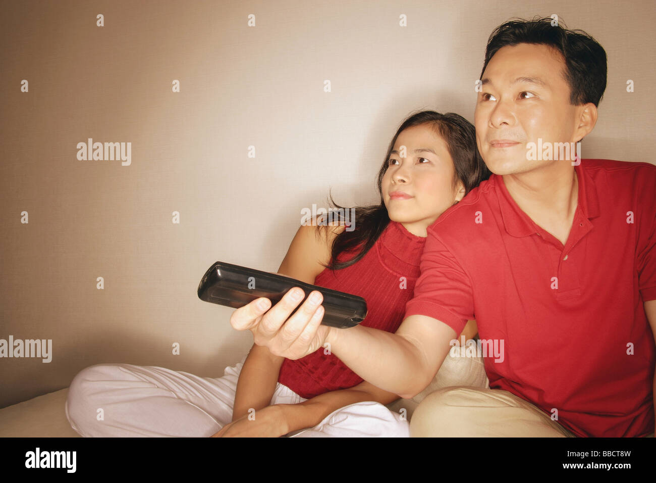 Man and woman sitting side by side, man holding remote control Stock ...