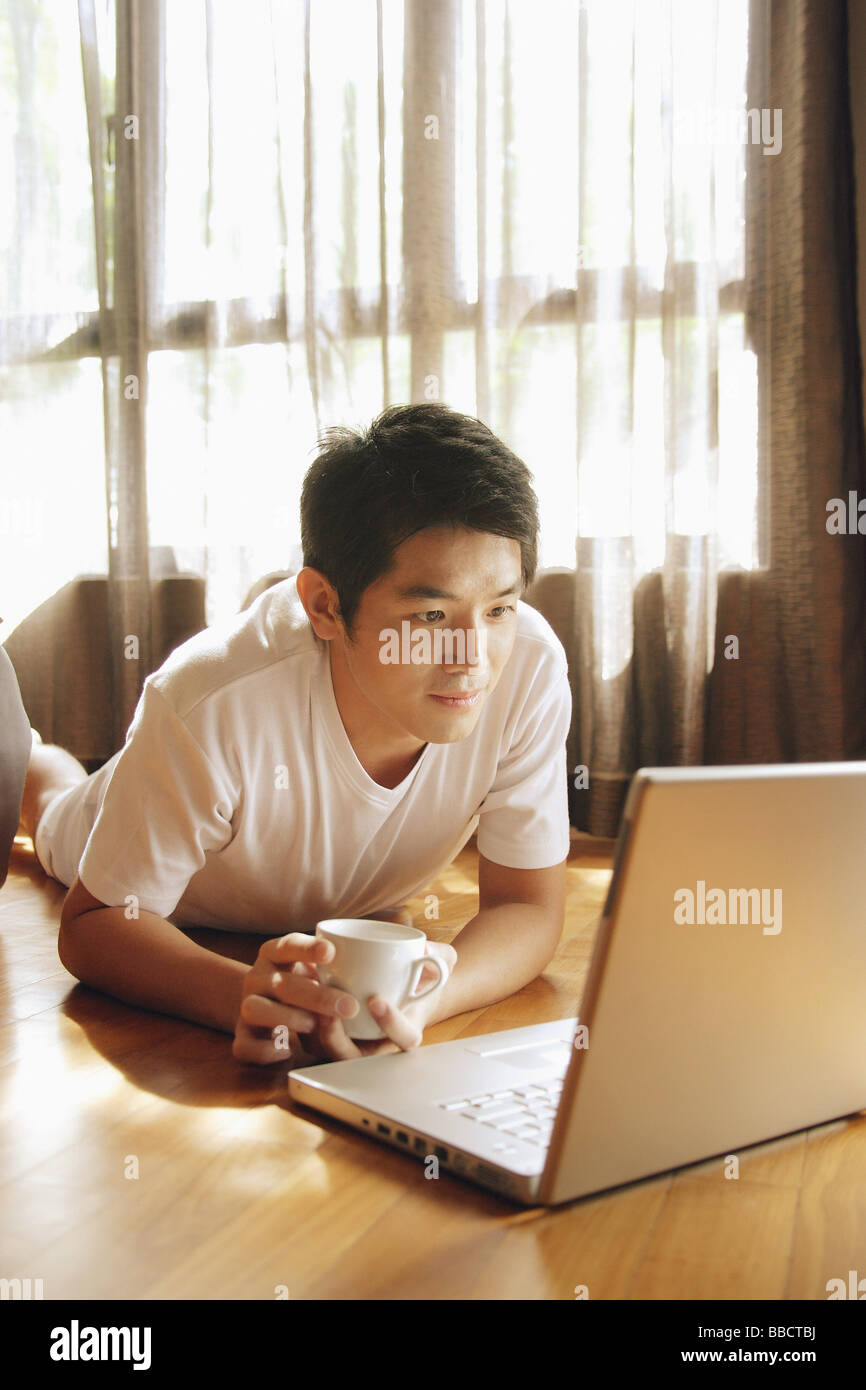Young man using laptop, lying on floor Stock Photo - Alamy