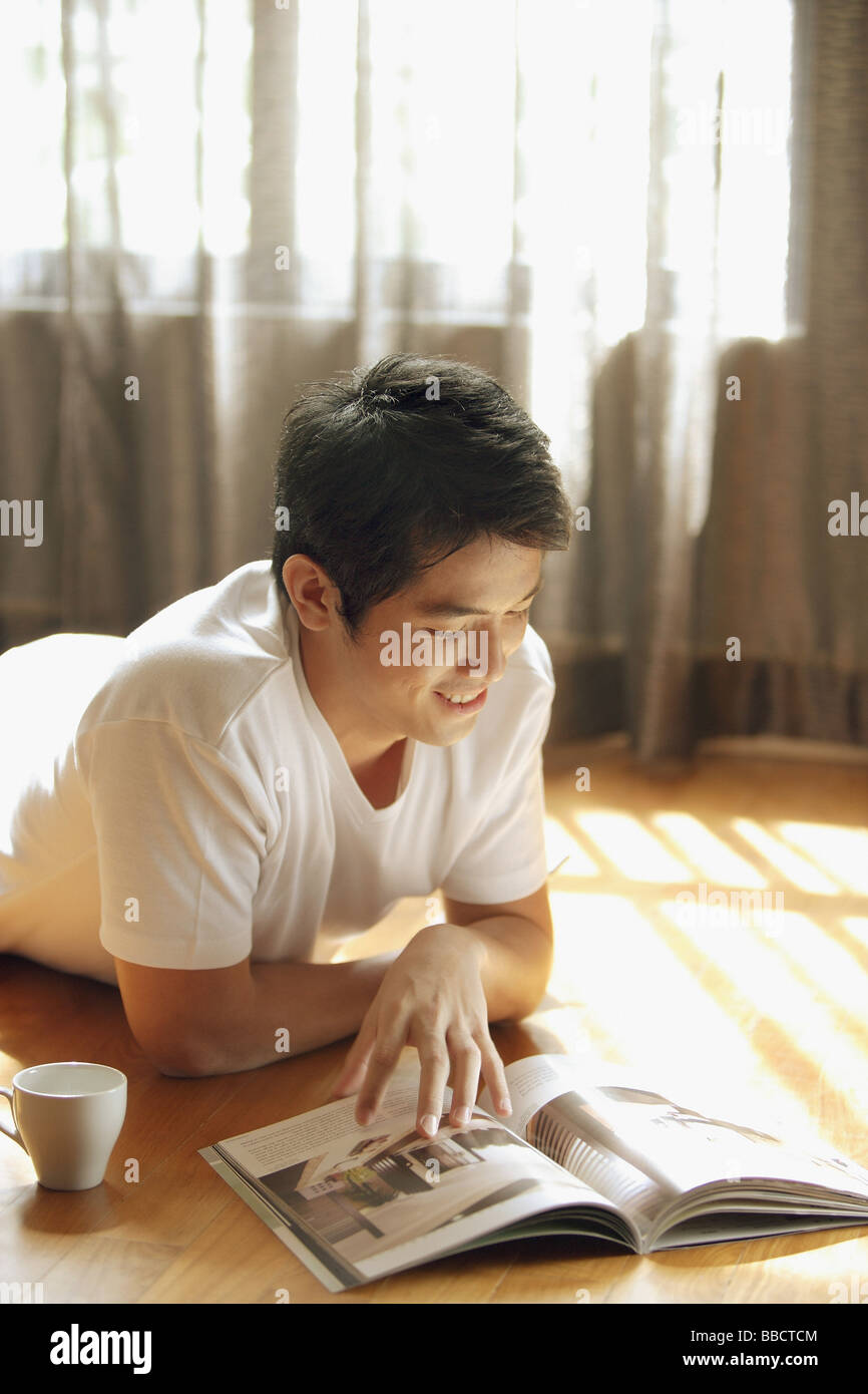 Young man reading magazine, smiling Stock Photo - Alamy