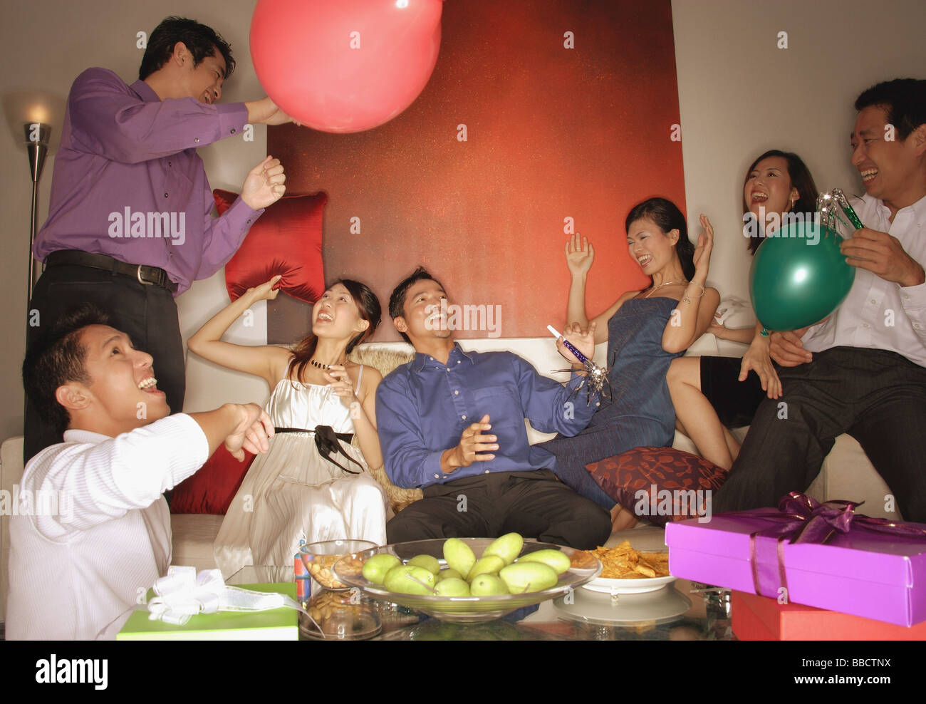 Group of friends having a party at home, holding balloons Stock Photo ...