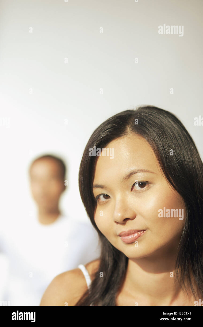 Young woman looking at camera, man behind her Stock Photo - Alamy