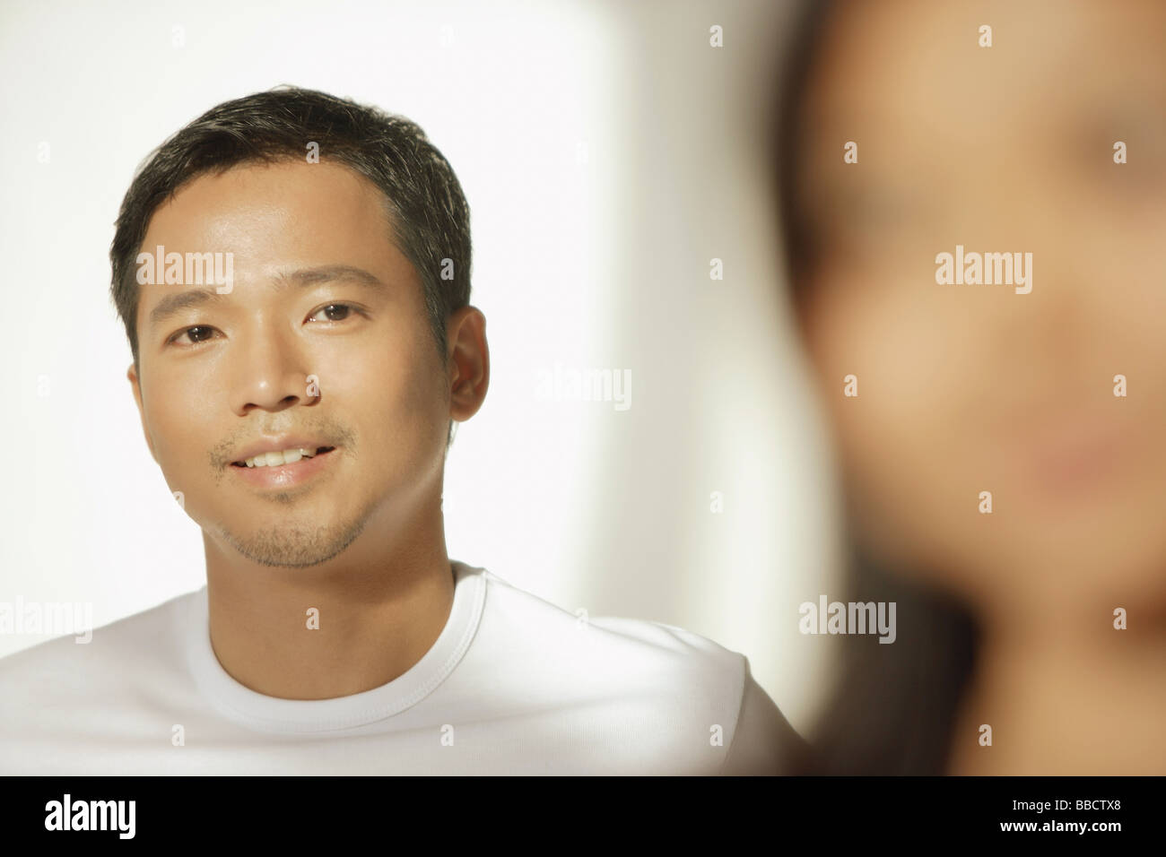 Young man looking at camera, woman in front of him Stock Photo - Alamy