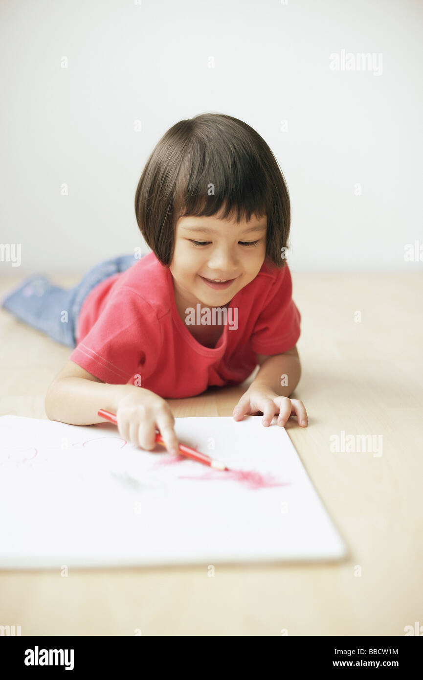 Young girl drawing on drawing pad, lying on front Stock Photo - Alamy